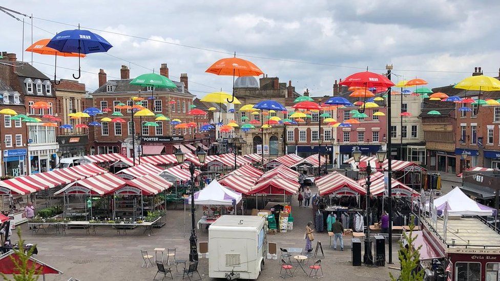 Hundreds of brightly-coloured umbrellas appear above market - BBC News