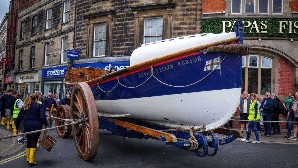 Whitby's historic lifeboat hand-pulled through seaside streets - BBC News