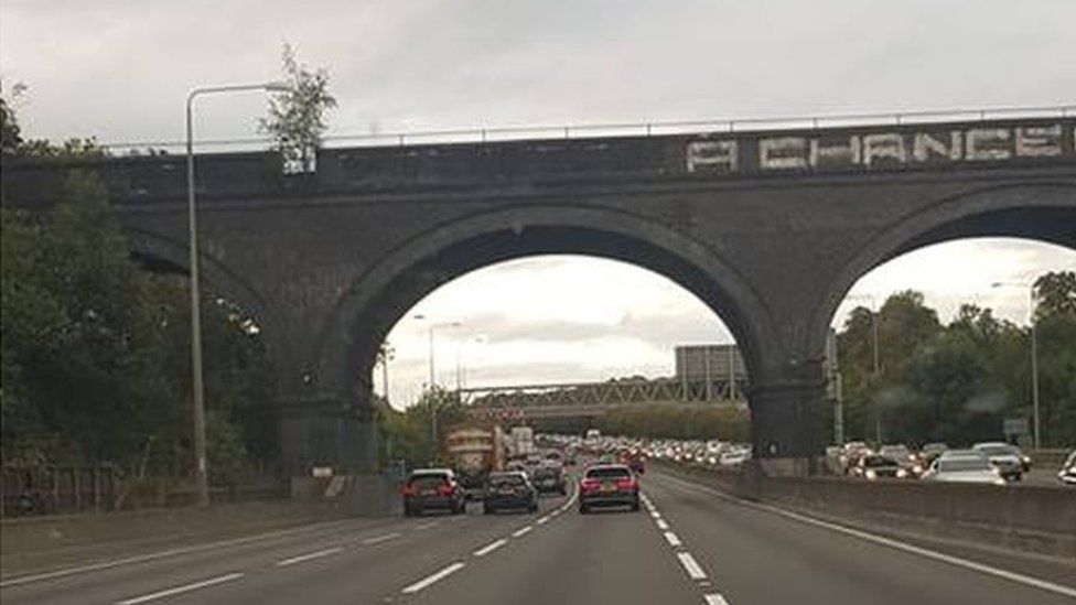 'Give peas a chance' M25 bridge graffiti removed - BBC News