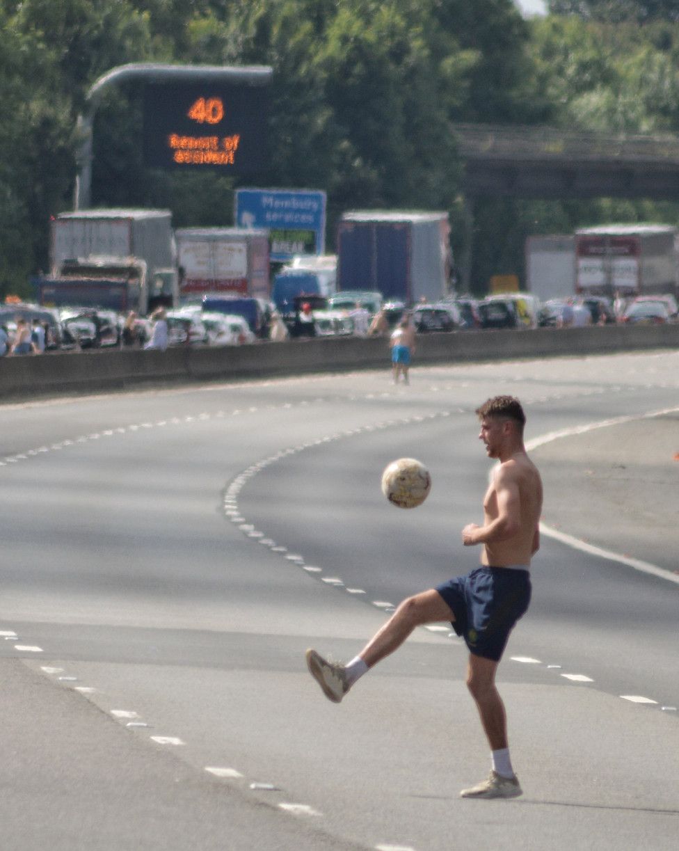 Man stuck in M4 jam plays football on carriageway - BBC News