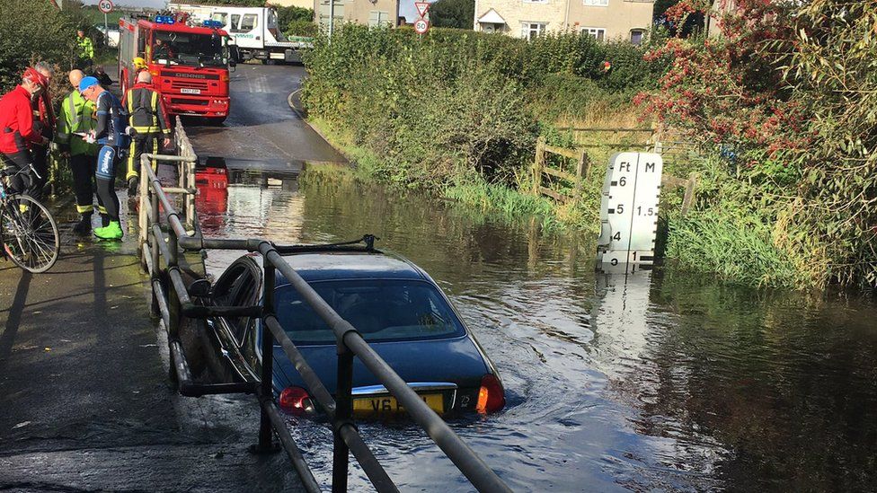 Cyclists rescue three from car at flooded ford - BBC News