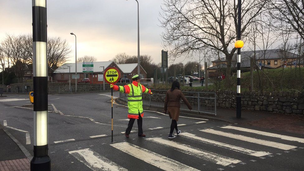 Lollipop lady 'banned' from high-fiving school pupils - BBC News