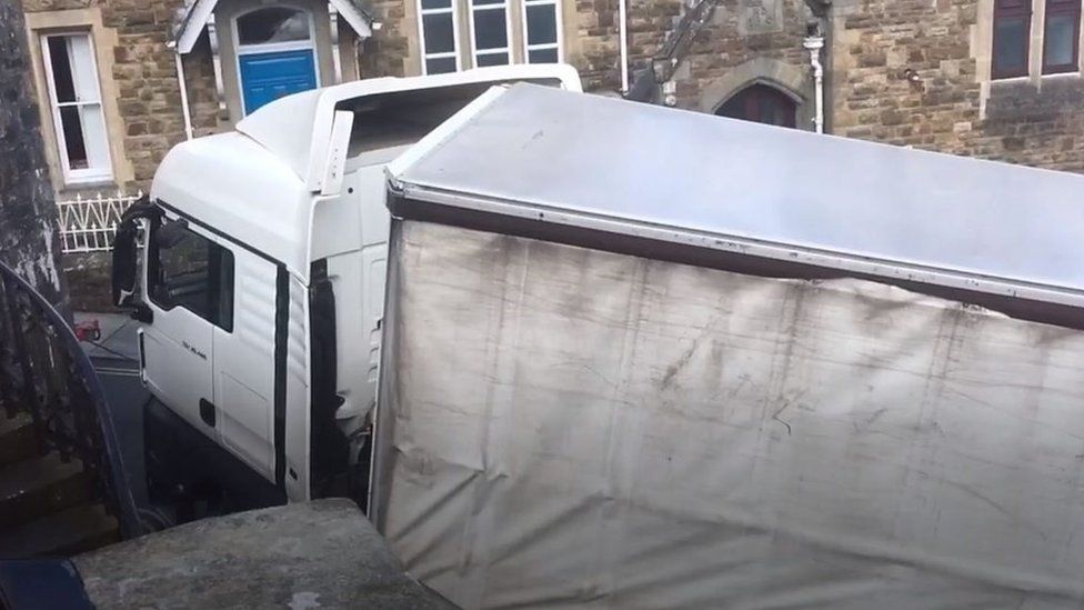 House damaged after lorry gets stuck on steep bend - BBC News