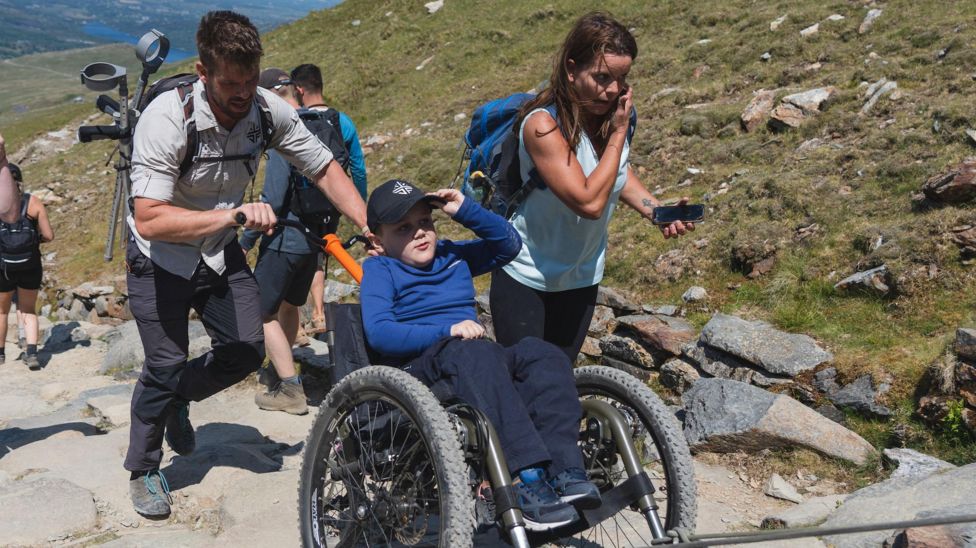Former rugby player climbs mountain with boy with rare condition - BBC News