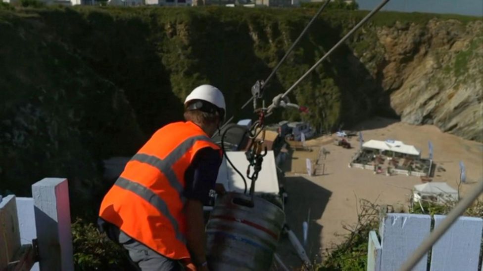 Cornwall beach bar turns to zip line for delivery of beer kegs - BBC News